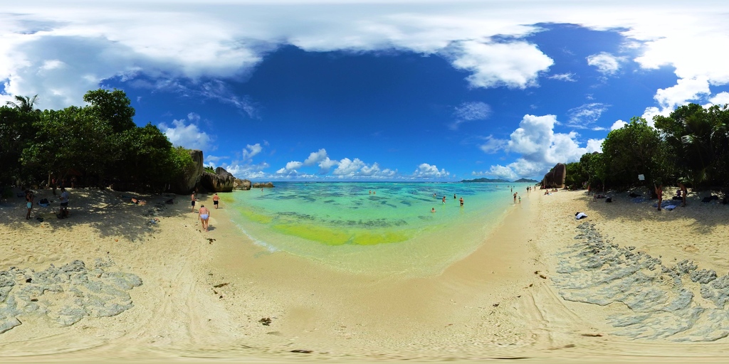 Busy beach with clear waters and lush greenery. La Digue, Seychelles ...